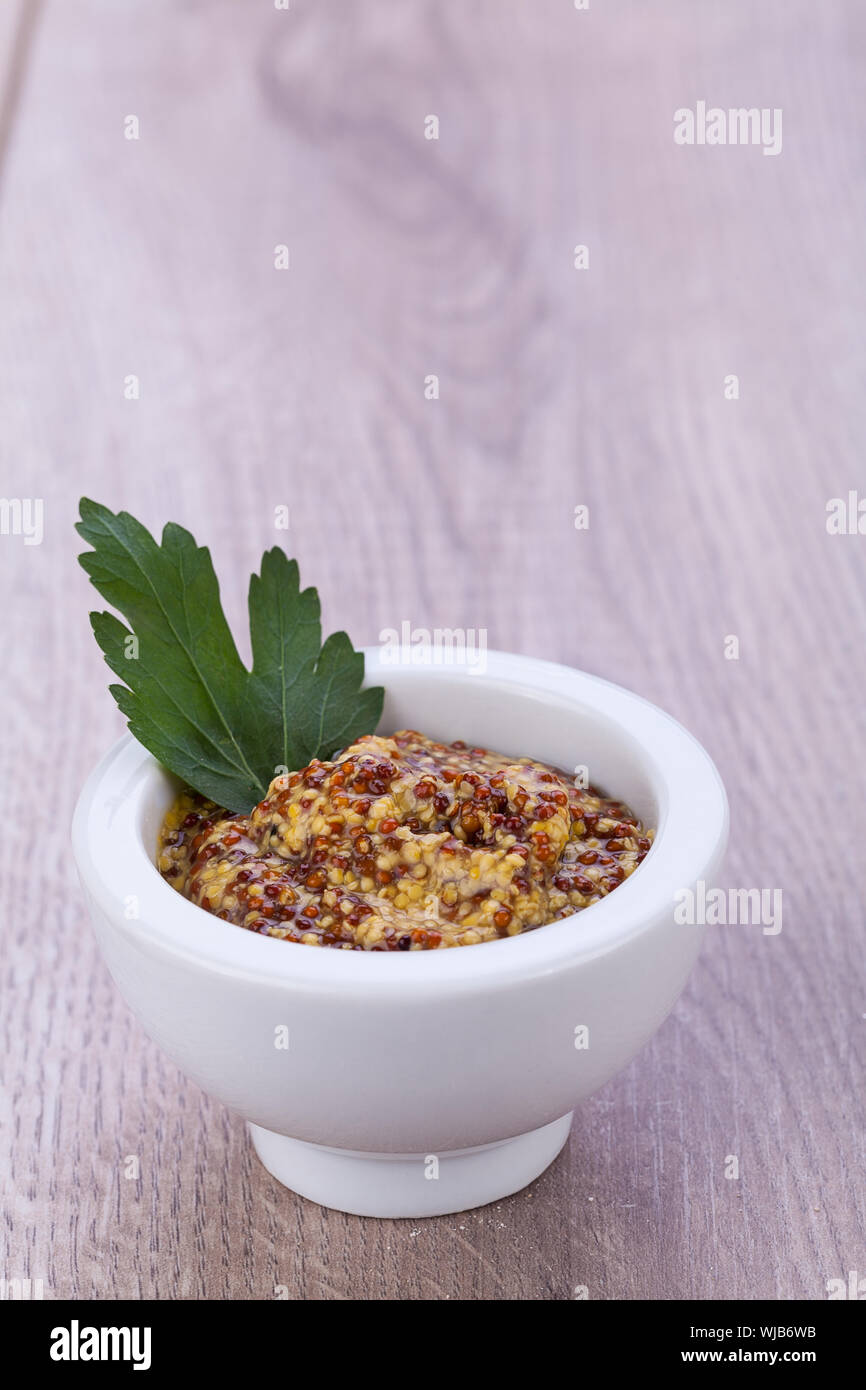 fresh yellow mustard in white bowl with parsley decorated detail macro ...