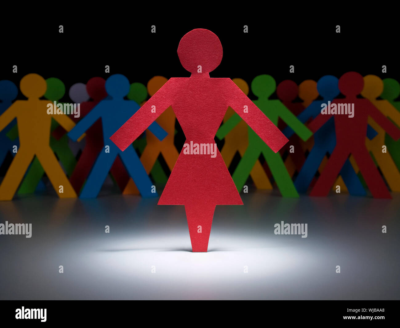 A female paper figure stands under the spotlight in front of multicolor ...