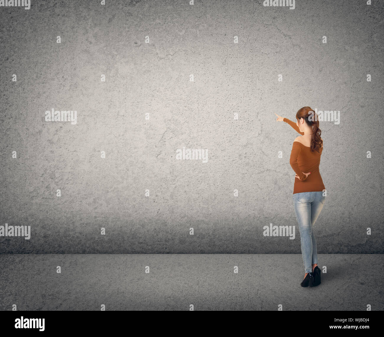 Asian young woman point somewhere on the wall, full length portrait ...