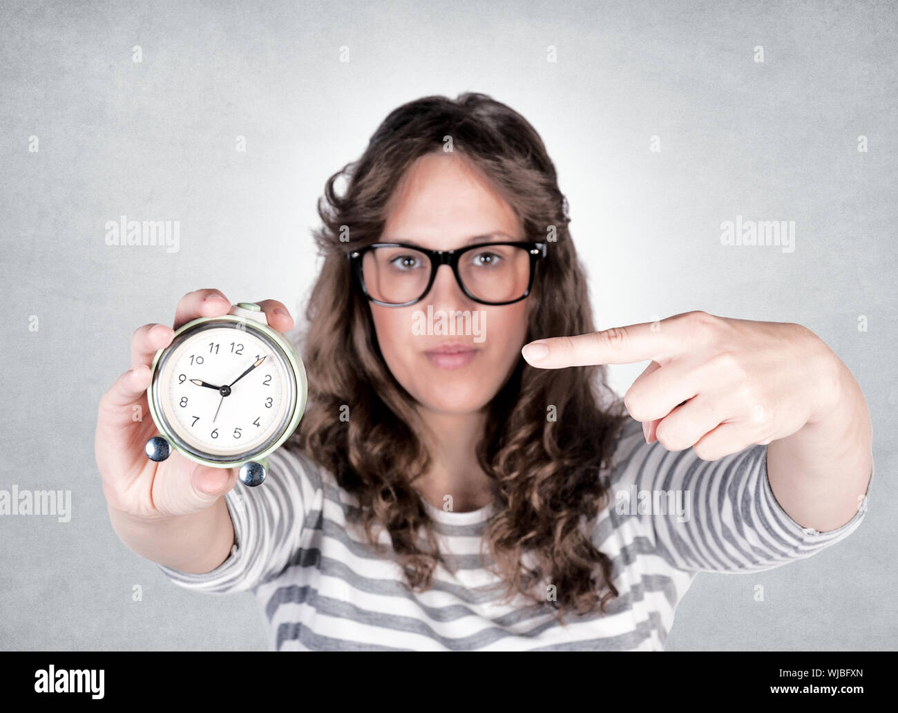 Female pointing her finger on the clock. Selective focus on hand and ...