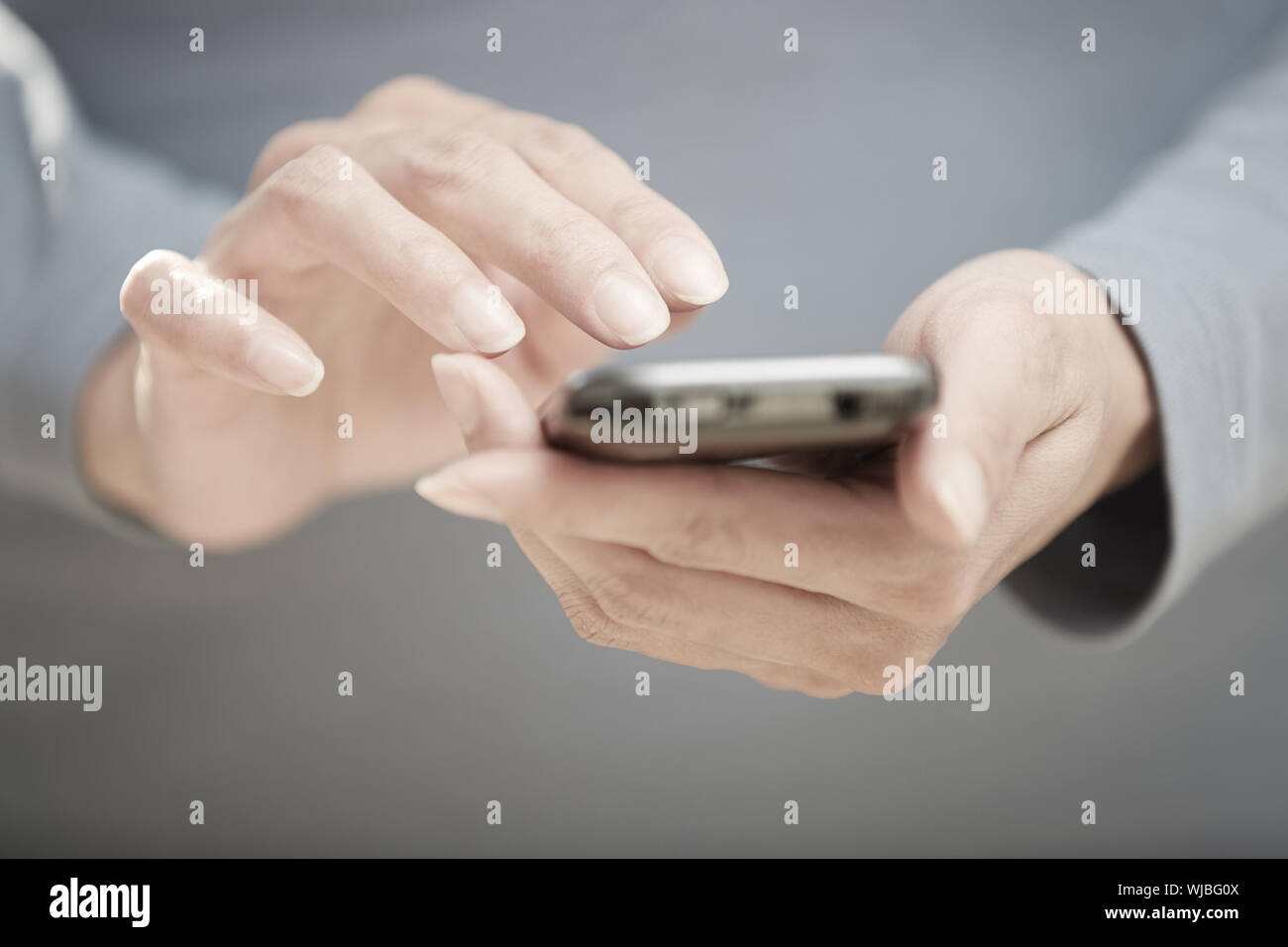 Human hands sending SMS via cell phone Stock Photo - Alamy