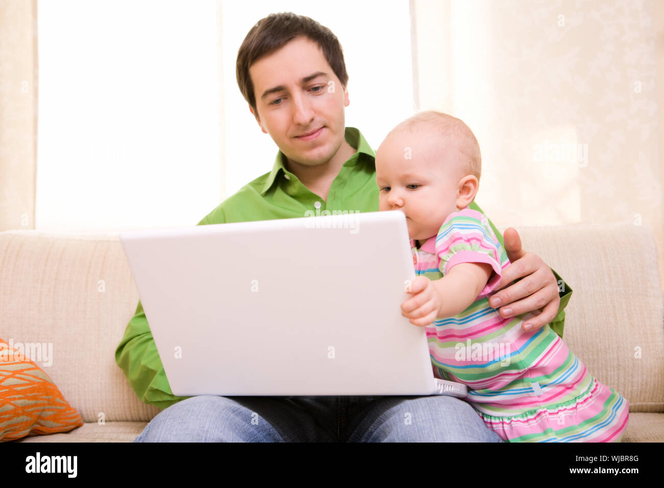 Father working on laptop from home while babysitting his daughter Stock ...