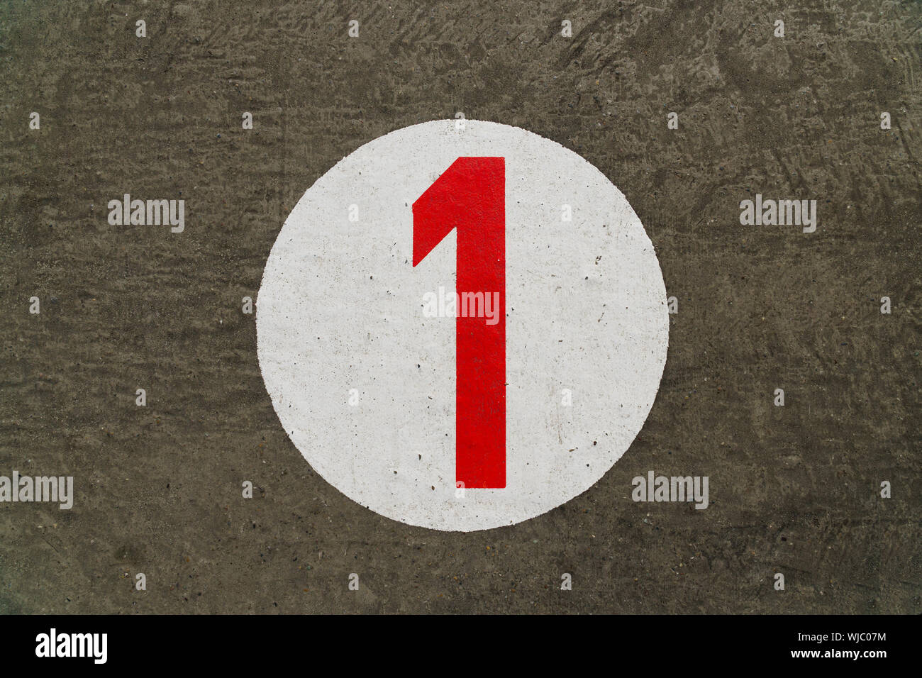 Red number one inside white circle painted on concrete background, top ...