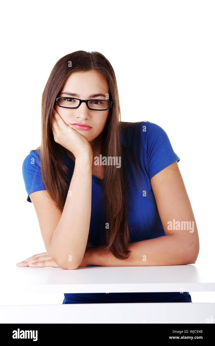 Young student woman bored, sitting by the desk. Isolated on white Stock ...