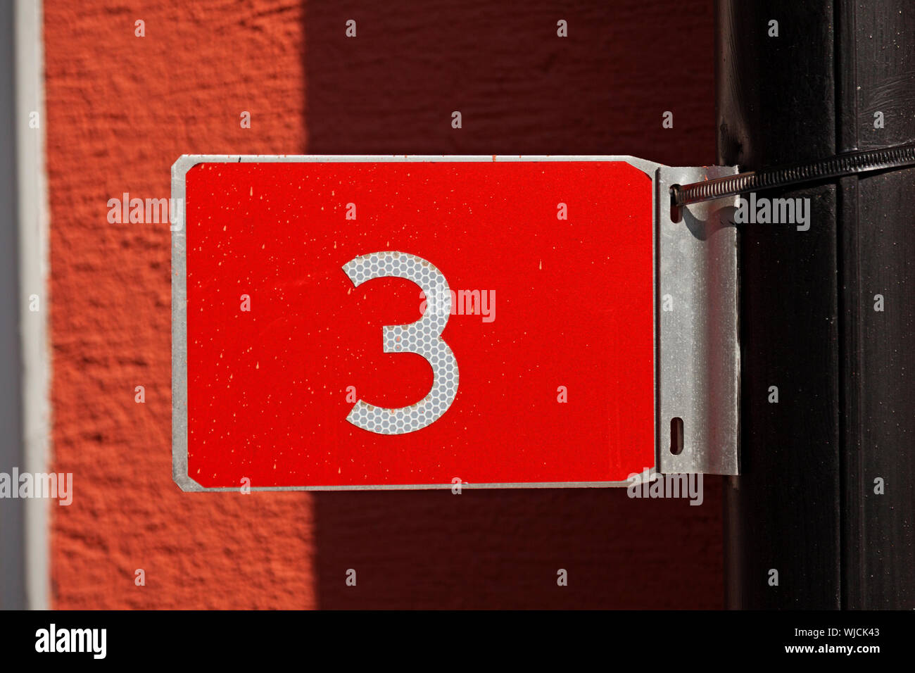 the number three on a red sign with reflective white text mounted on a ...