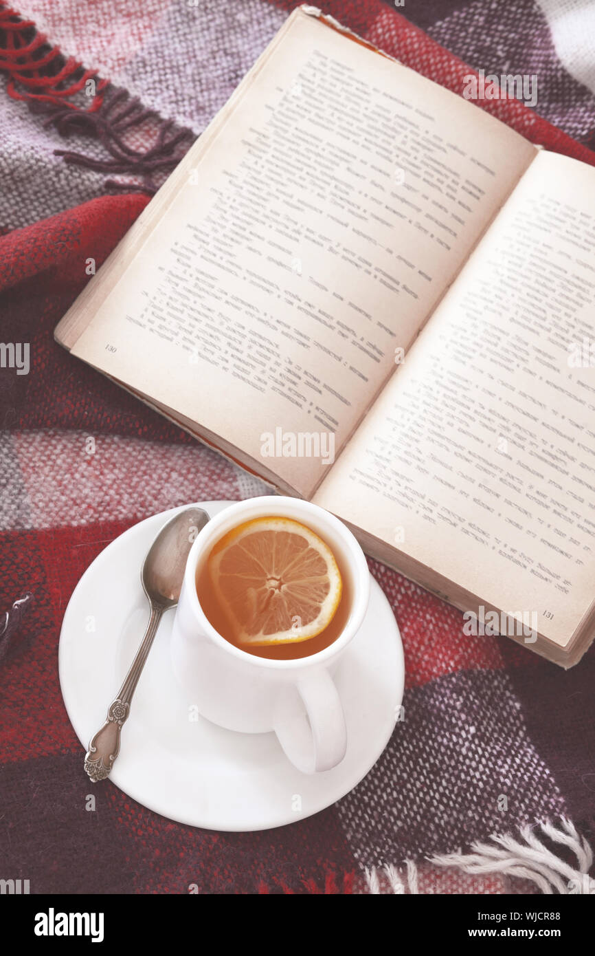 Cup of hot tea and reading on a blanket, instagram style toned. Top ...
