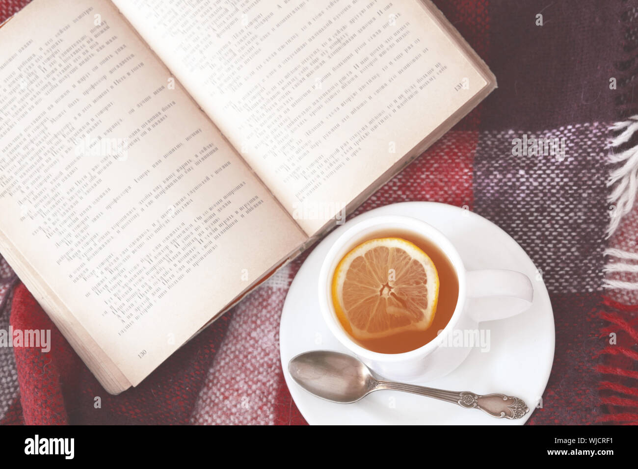 Cup of hot tea and reading on a blanket, instagram style toned. Top ...