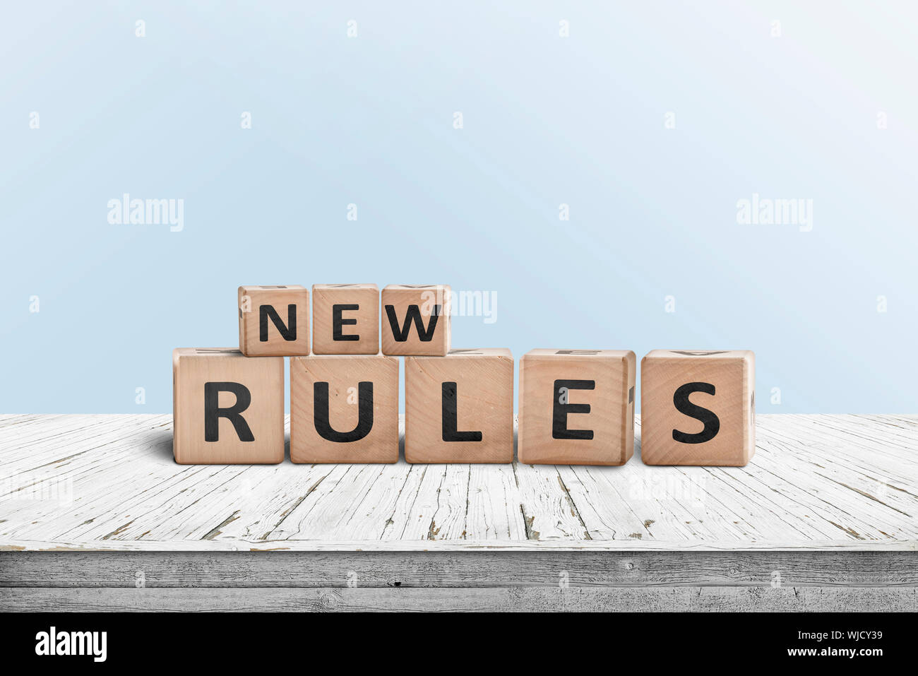New rules sign made of wood on a desk in a room with a blue background ...