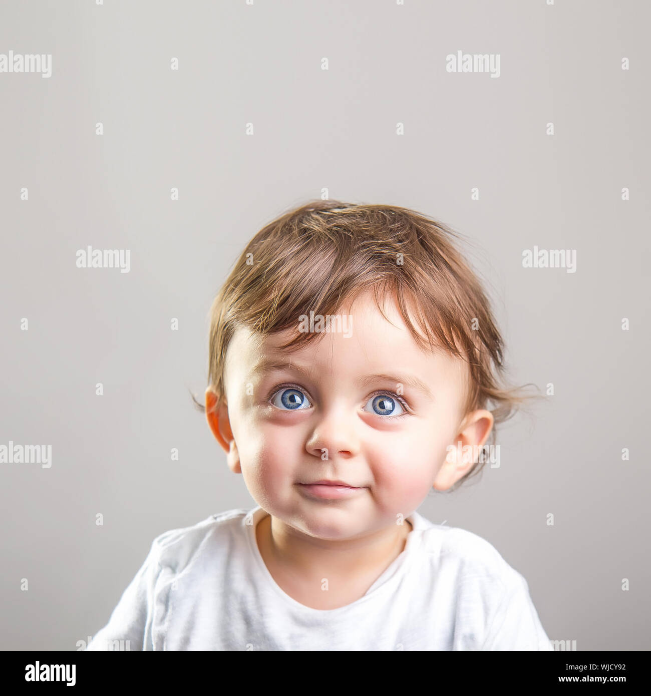 Blue eyed baby looking up and smiling Stock Photo - Alamy