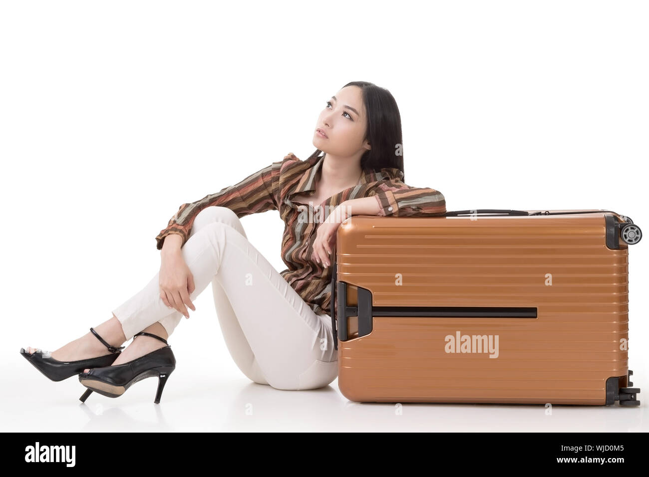 Modern Asian woman sit on ground with a luggage, full length portrait ...