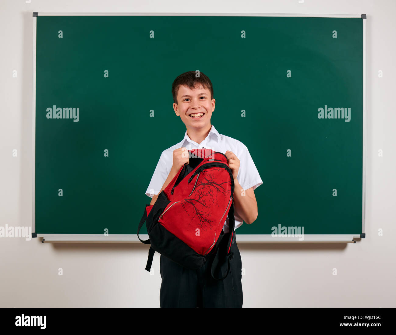 Portrait of a school boy looking for school supplies in his backpack ...