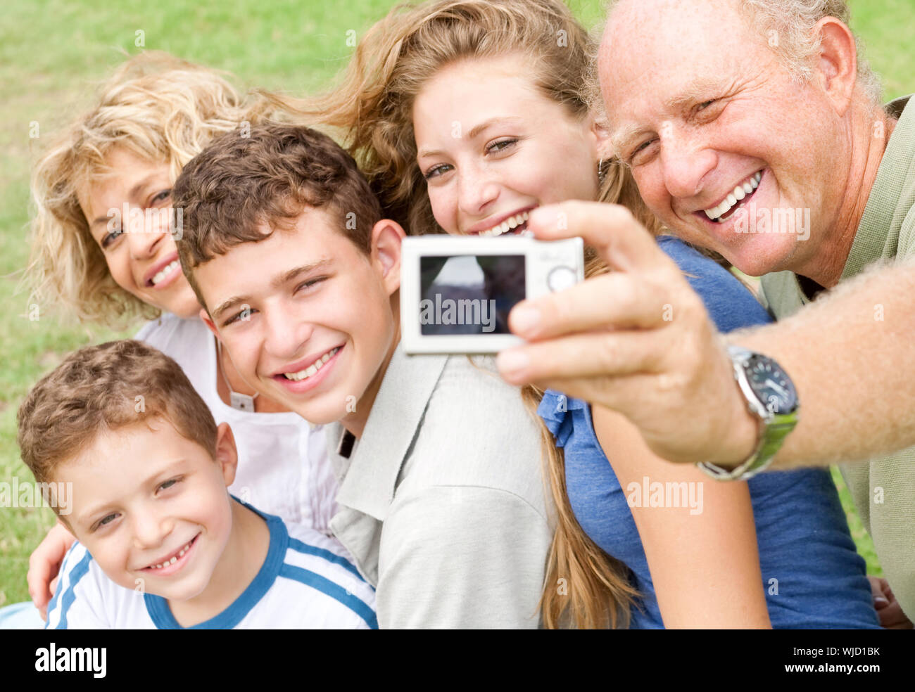 Happy family of five smiling at camera as grandfather clicks moment of ...