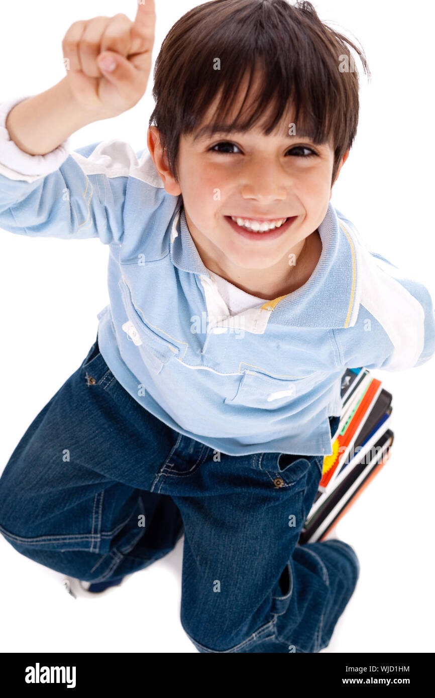 Little boy student pointing up and sitting over stack of books isolated ...