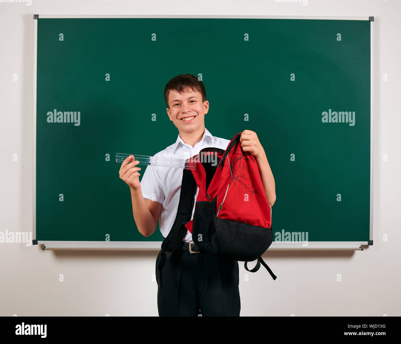 Portrait of a school boy looking for school supplies in his backpack ...