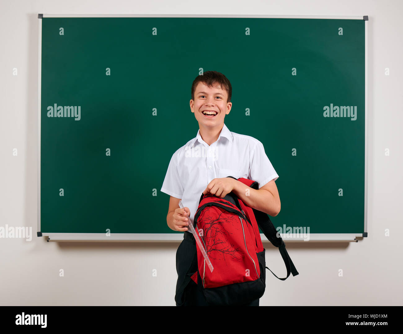 Portrait of a school boy looking for school supplies in his backpack ...