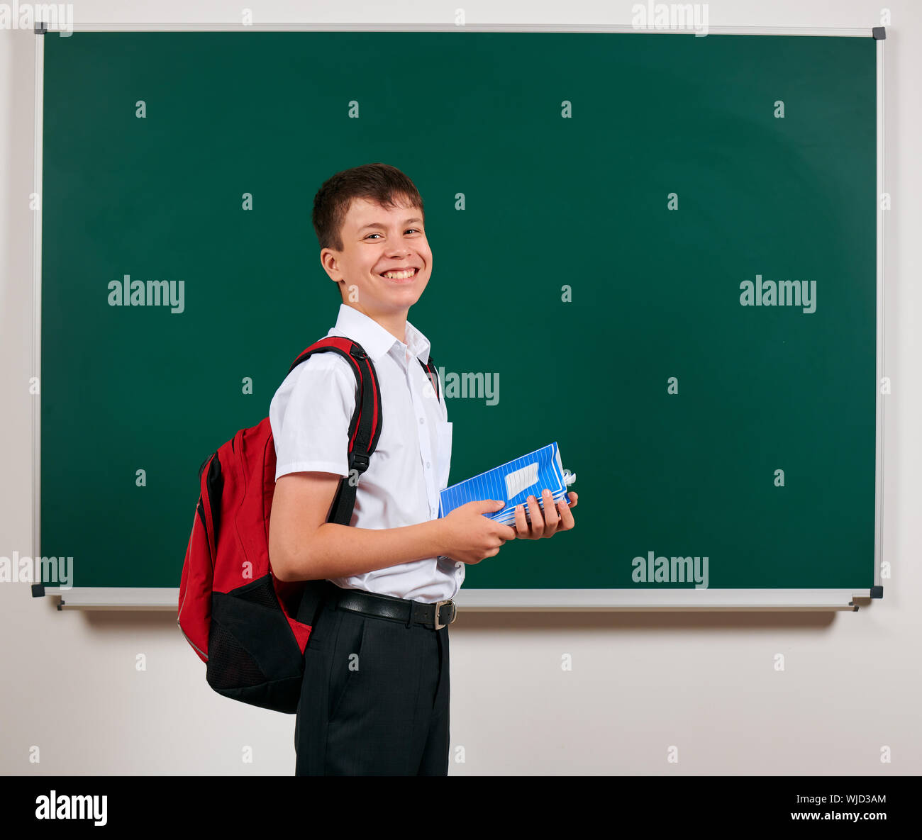 Portrait of a school boy posing with backpack and school supplies ...