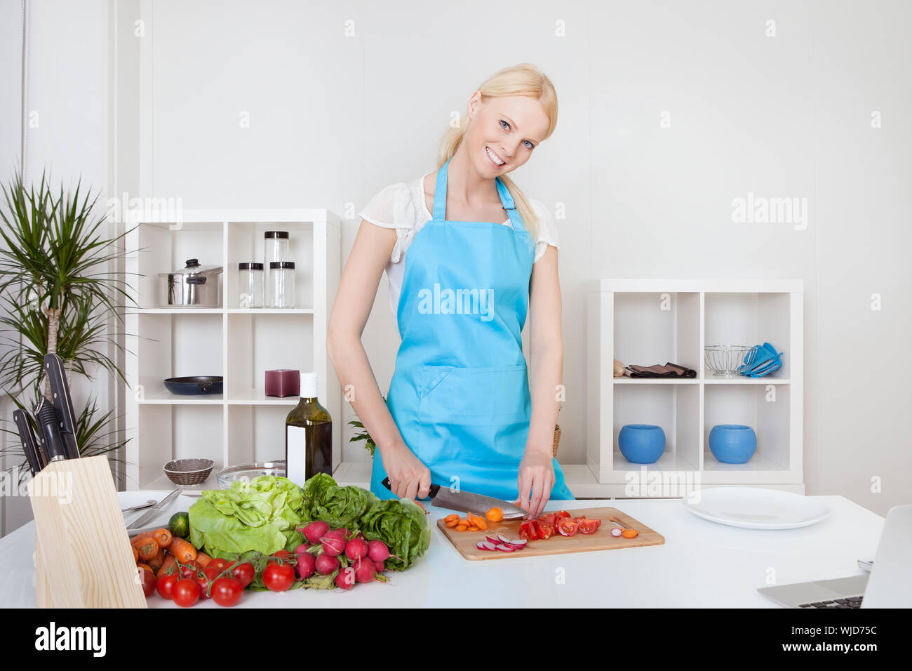 Cheerful young woman cooking in the kitchen Stock Photo - Alamy