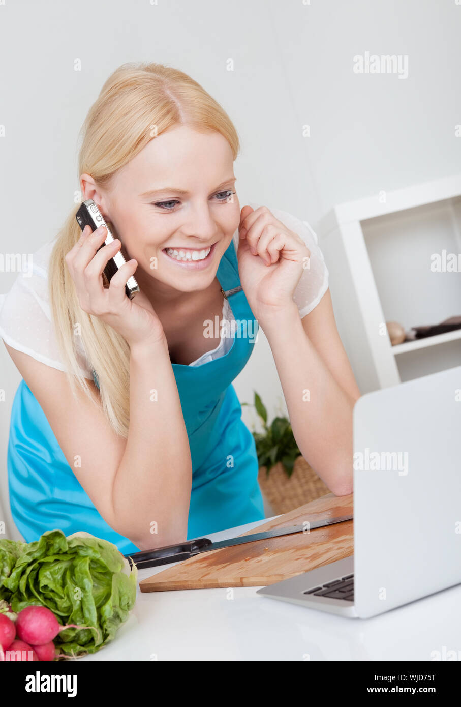 Cheerful young woman cooking in the kitchen Stock Photo - Alamy