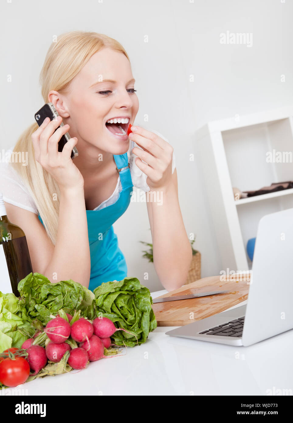 Cheerful young woman cooking in the kitchen Stock Photo - Alamy
