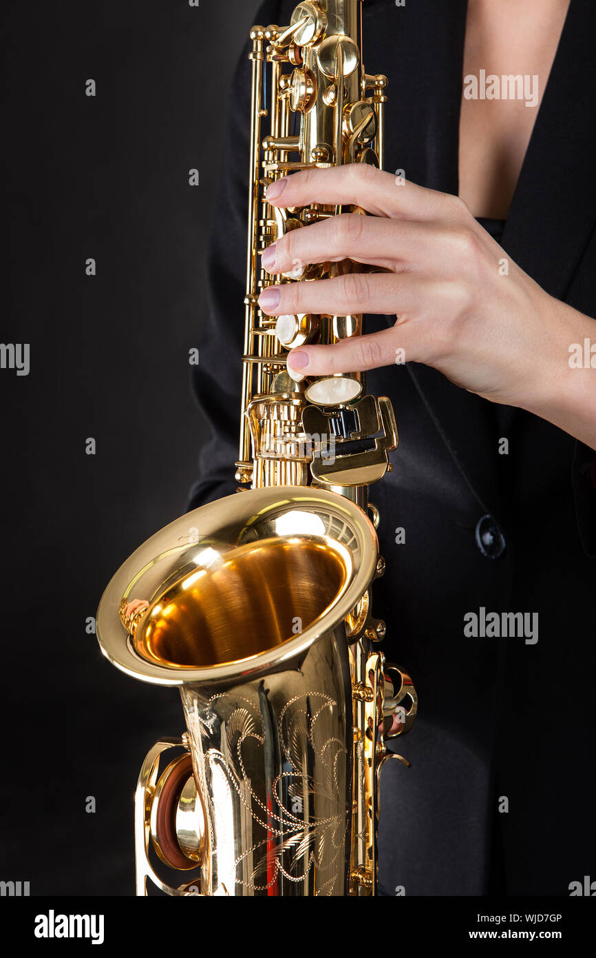 Beautiful young woman playing saxophone over black background Stock ...
