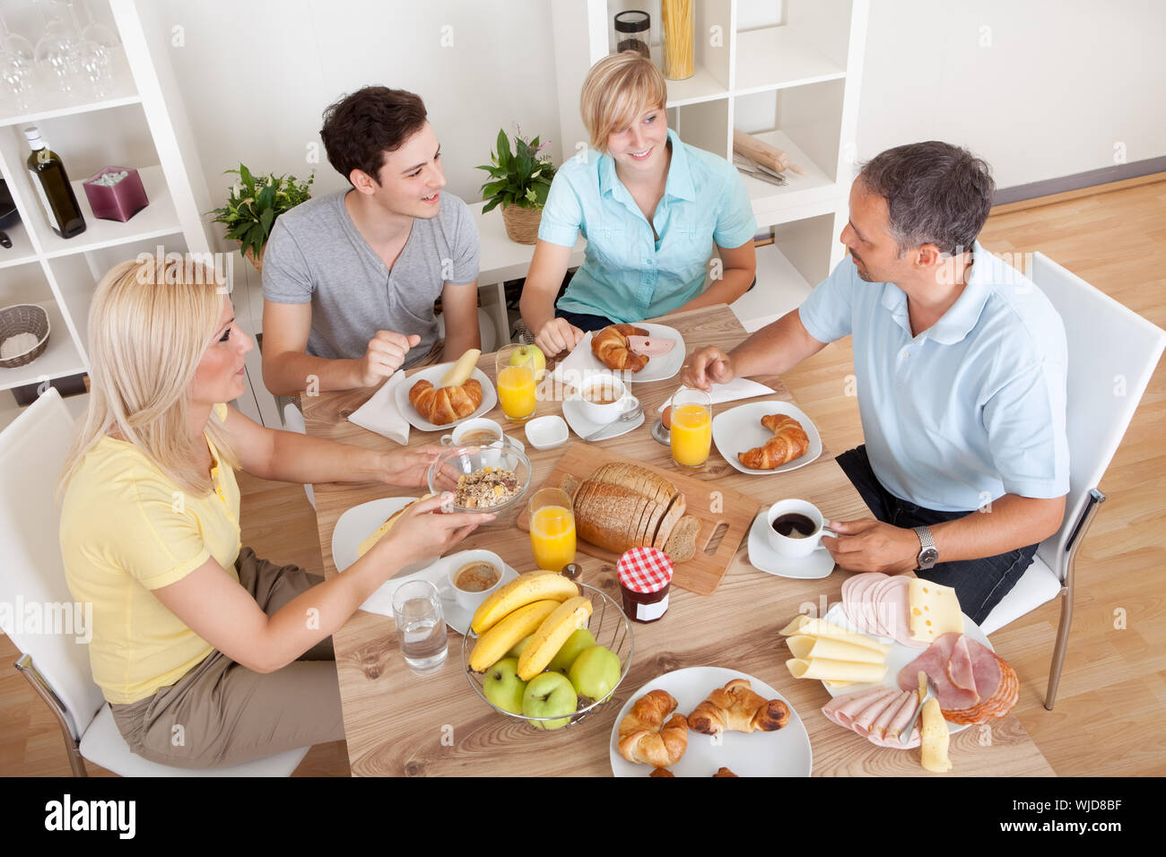 Happy family with two teenage children sitting around the table ...