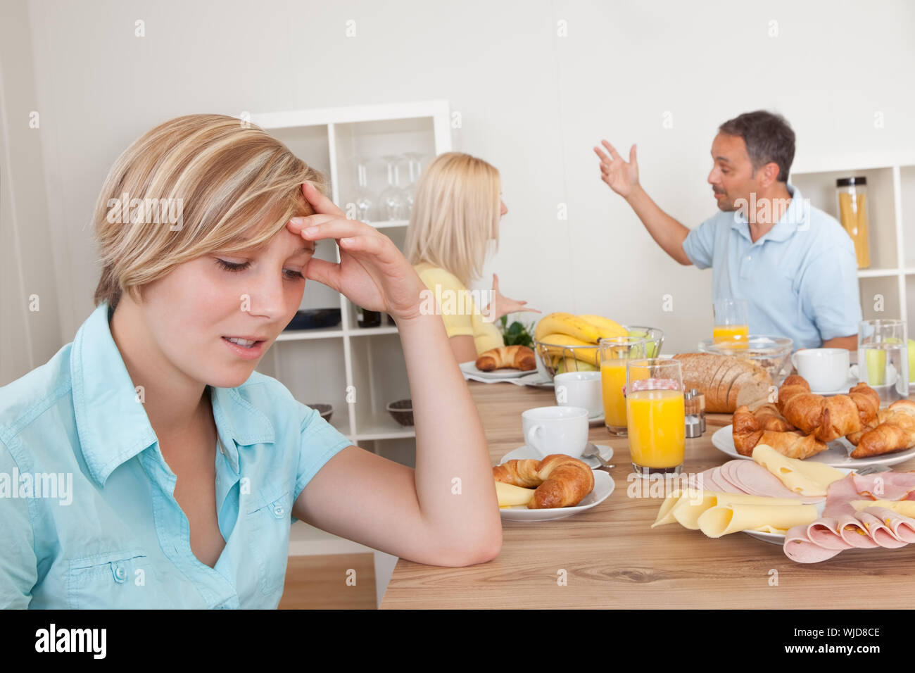 A young teenage daughter looks very downhearted and despondent at her ...
