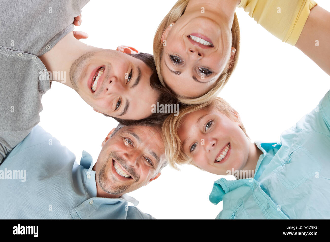 Happy family standing in a circle with their heads close together ...