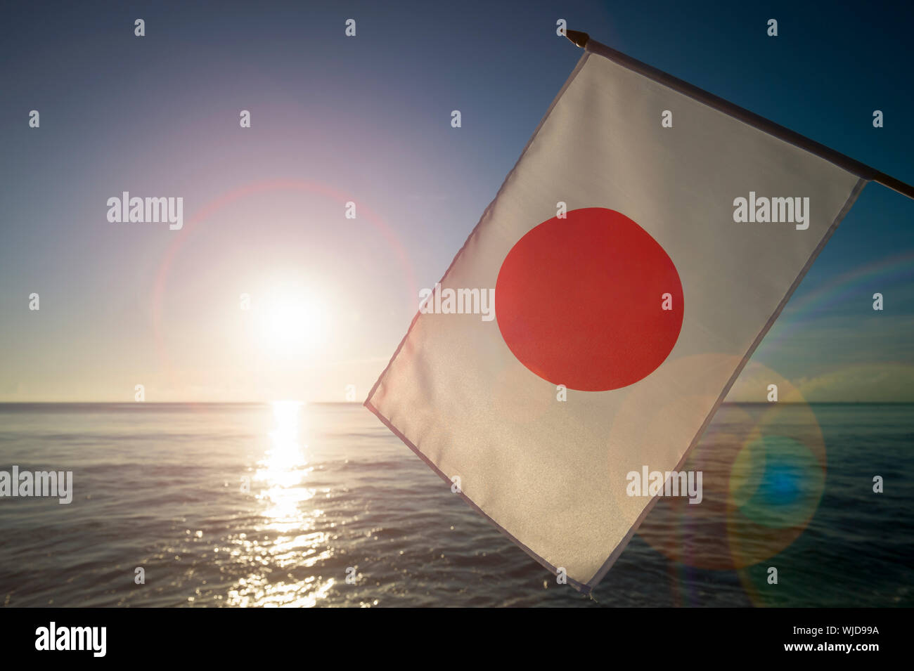 Golden sunrise view of Japanese flag hanging in front of calm seas with ...