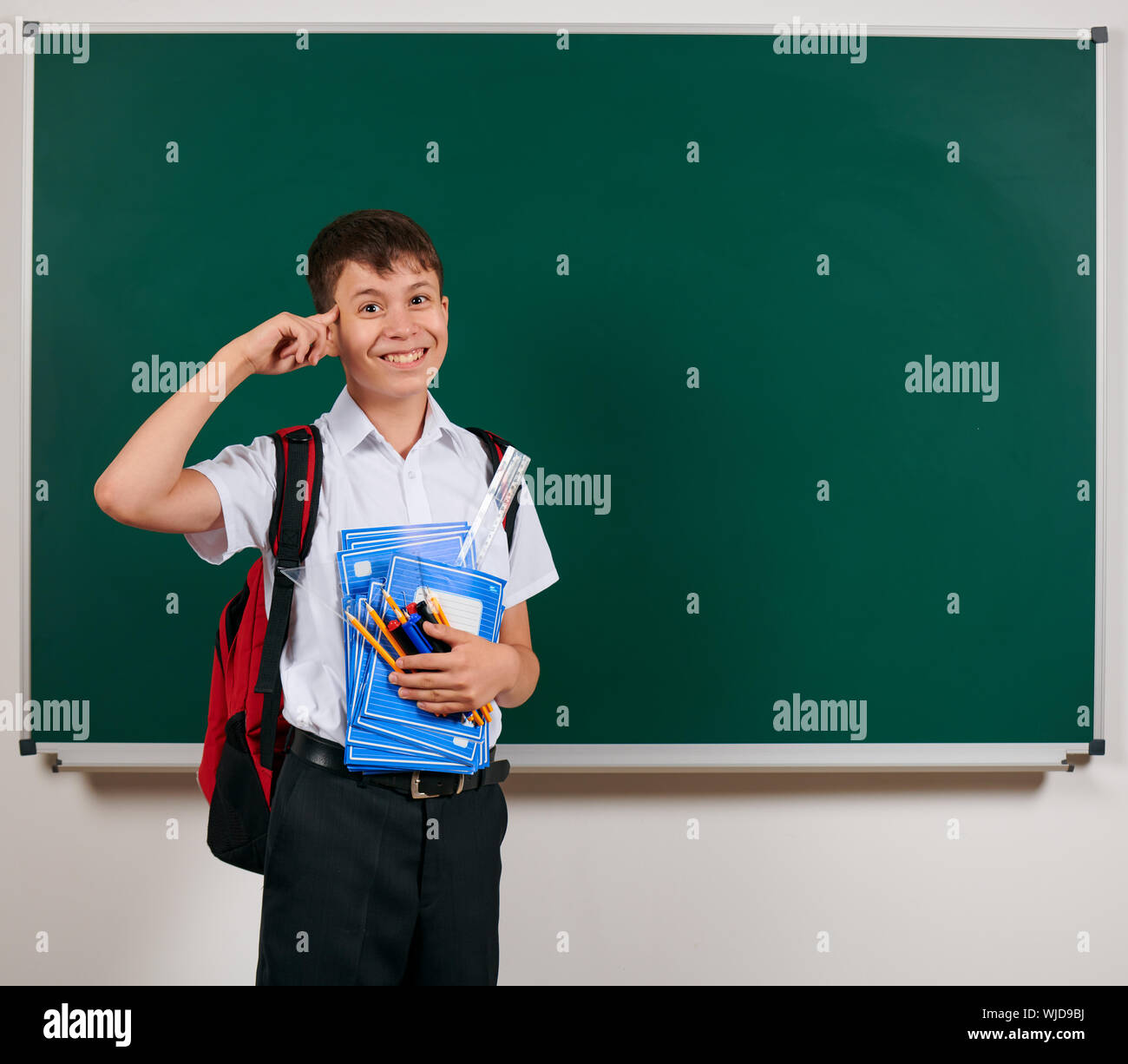 Portrait of a school boy posing with backpack and school supplies ...
