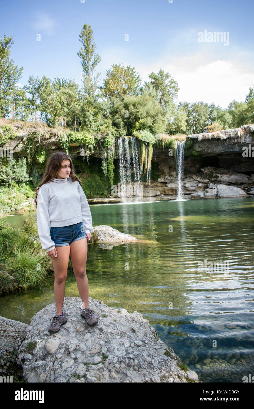 Relaxed pretty young girl posing in a lake with waterfall Stock Photo ...