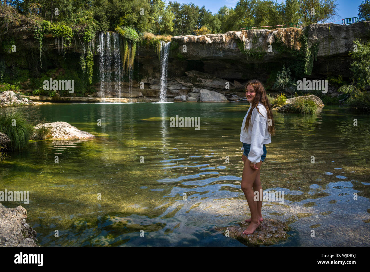 Relaxed pretty young girl posing in a lake with waterfall Stock Photo ...