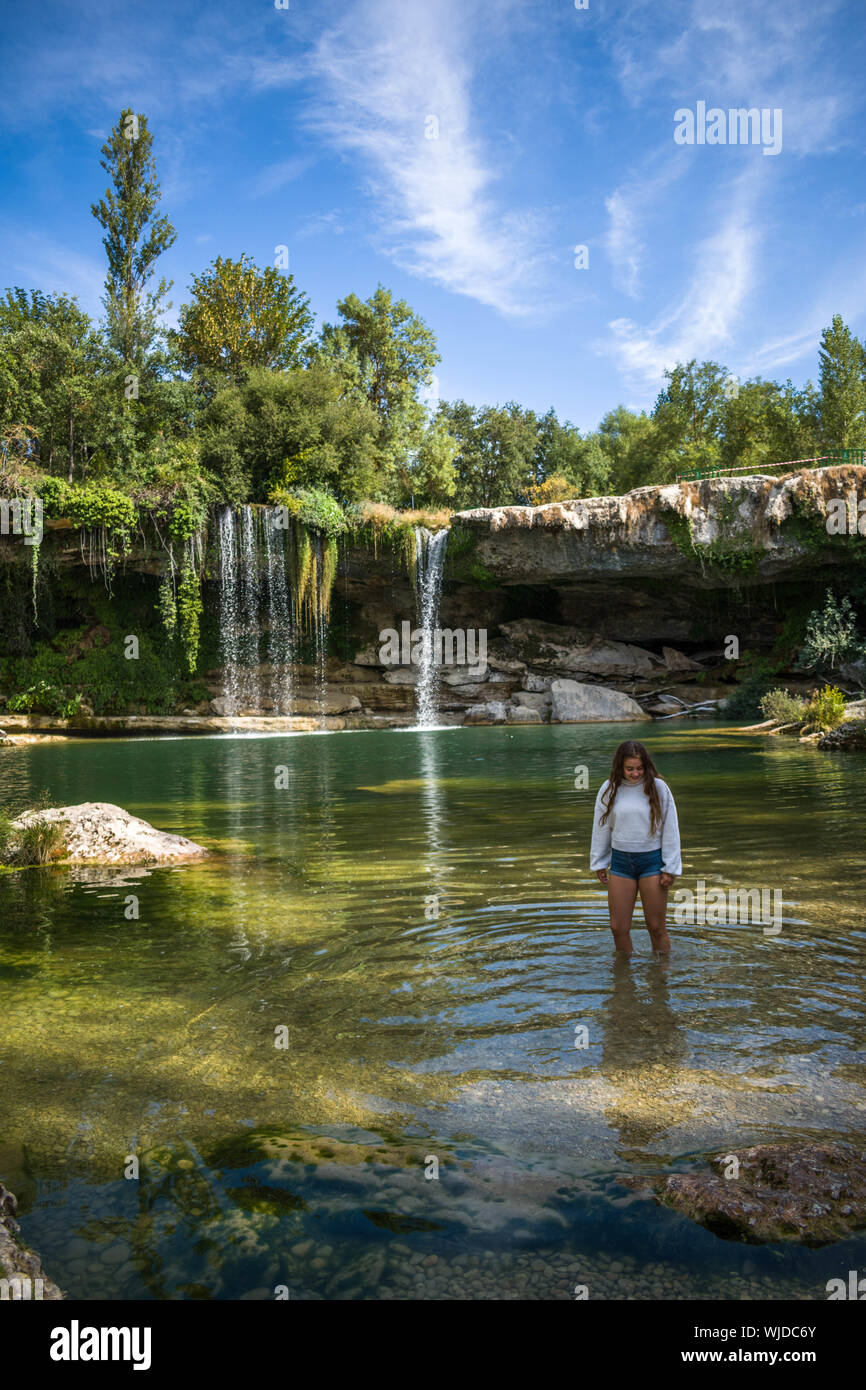 Relaxed pretty young girl posing in a lake with waterfall Stock Photo ...