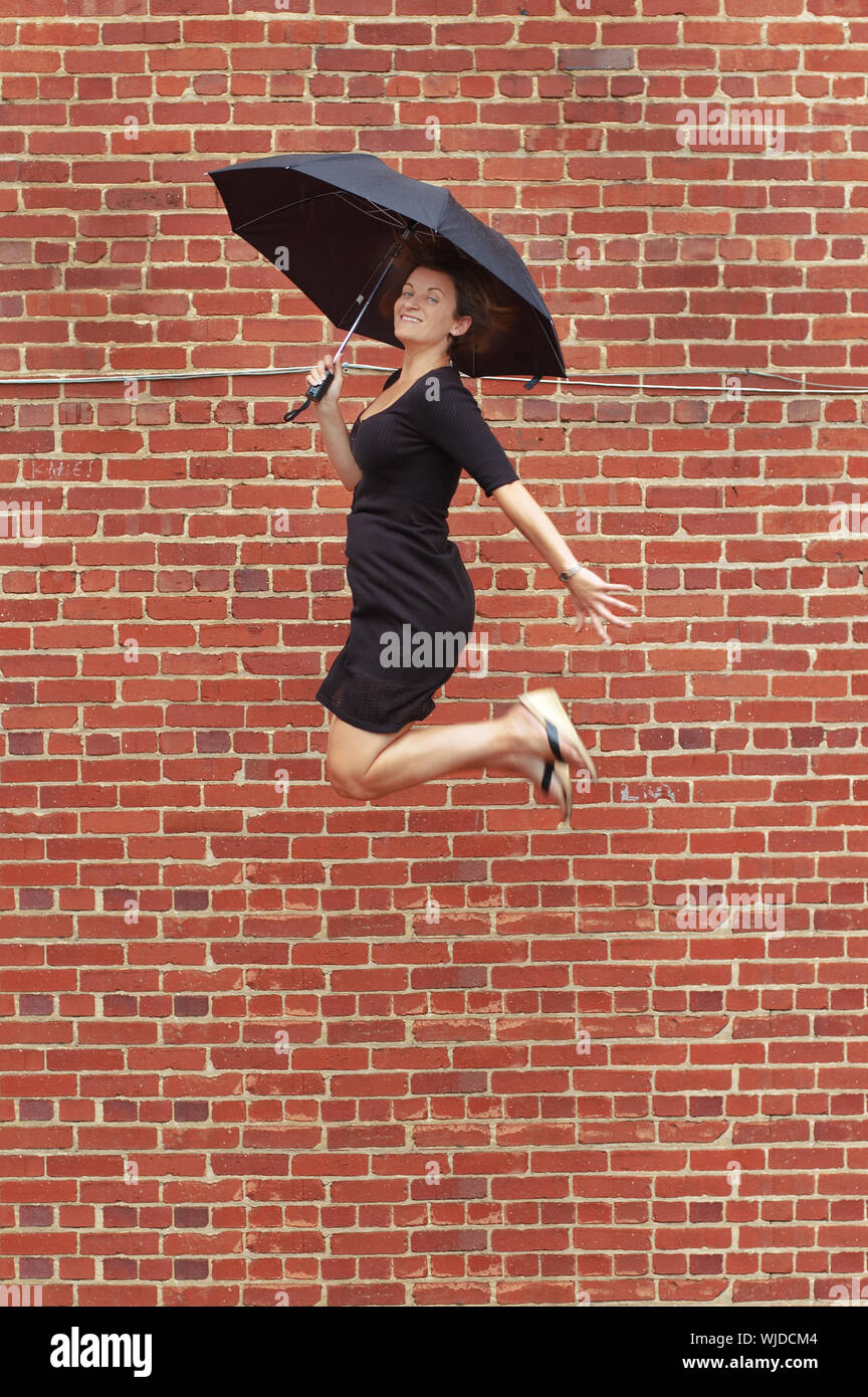 Lady jumping with umbrella high into air Stock Photo - Alamy