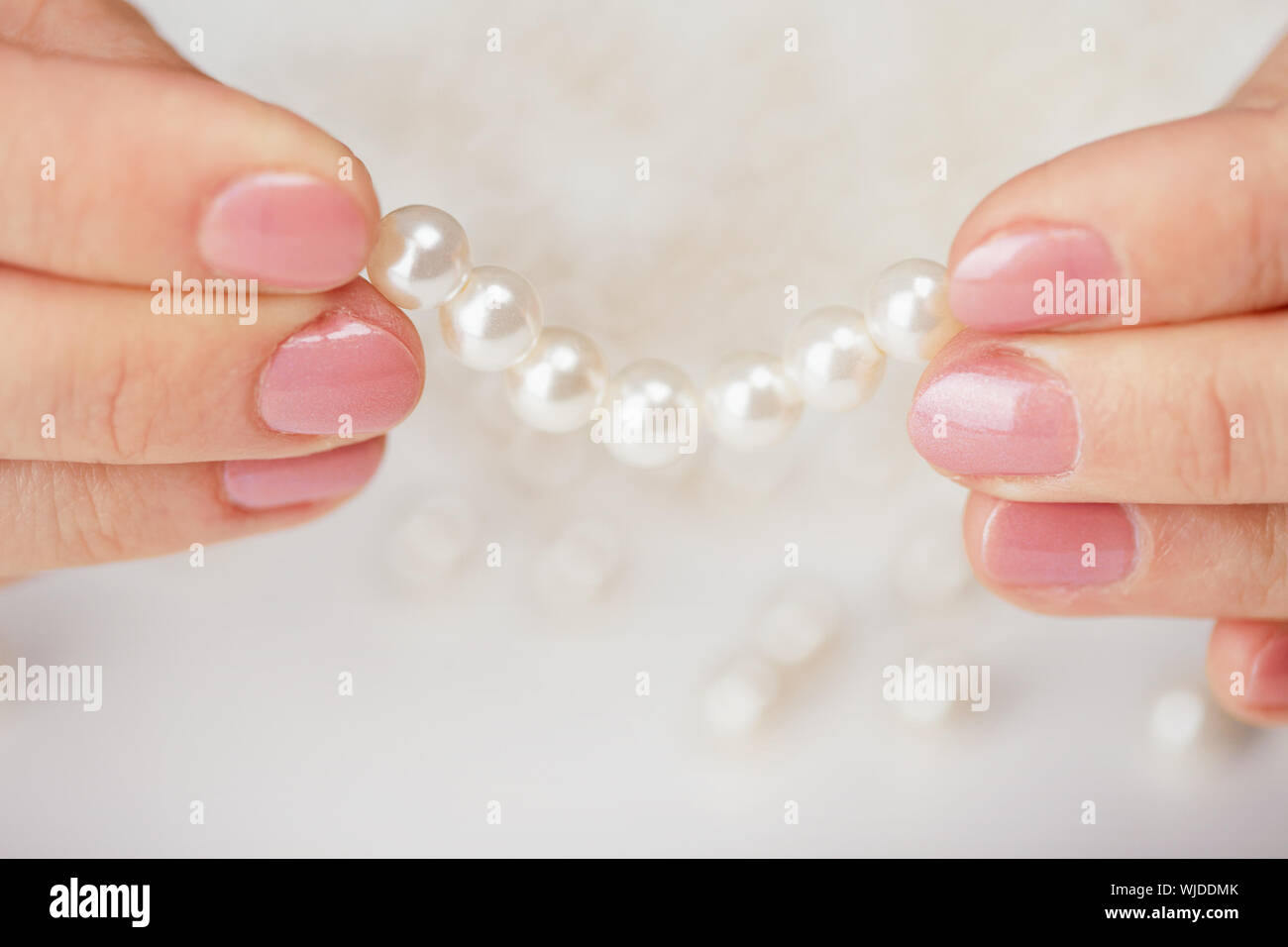 Female fingers hold a thread with several pearls Stock Photo - Alamy