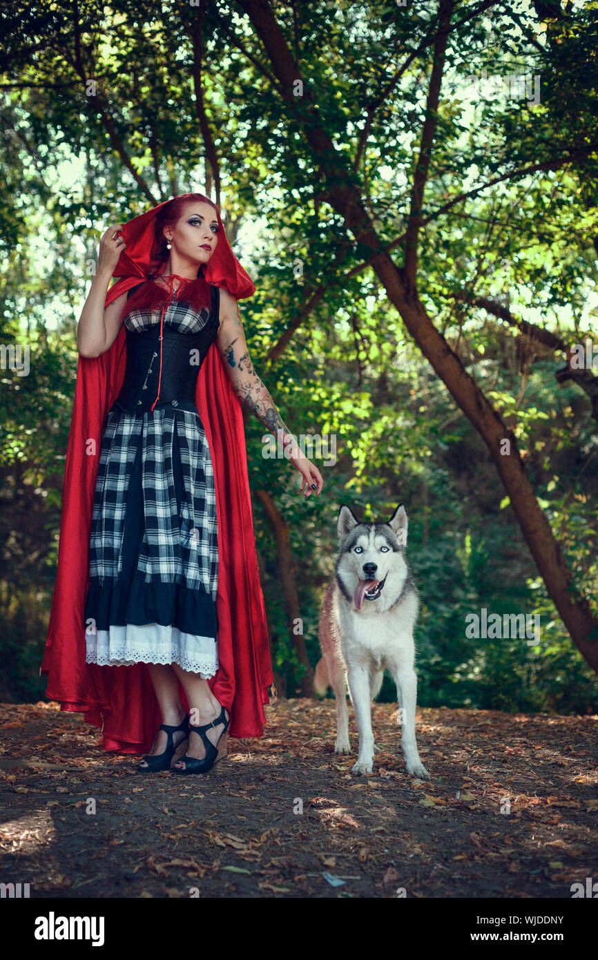 Attractive woman with the dog. Huskies. Woman in red cape with wolf ...