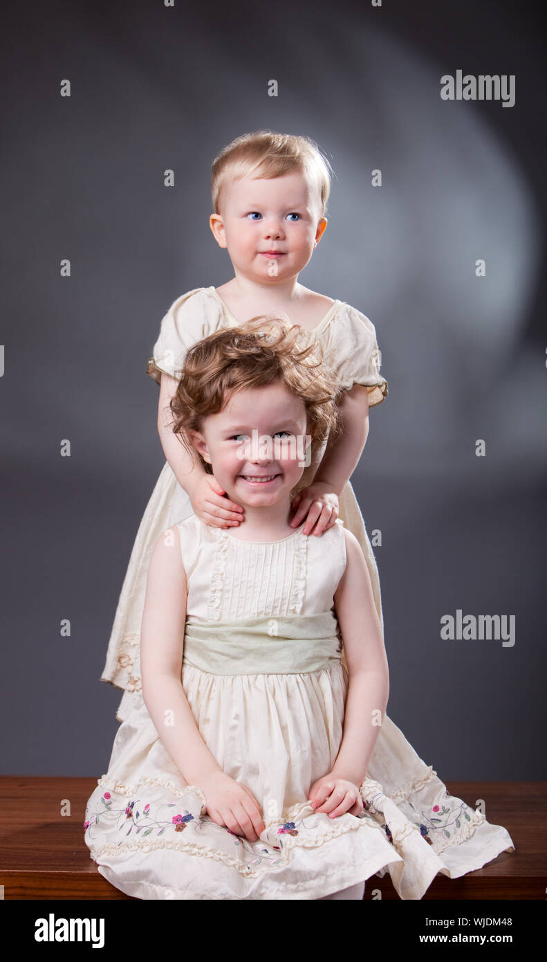 Studio photo of two sisters over gray background Stock Photo - Alamy