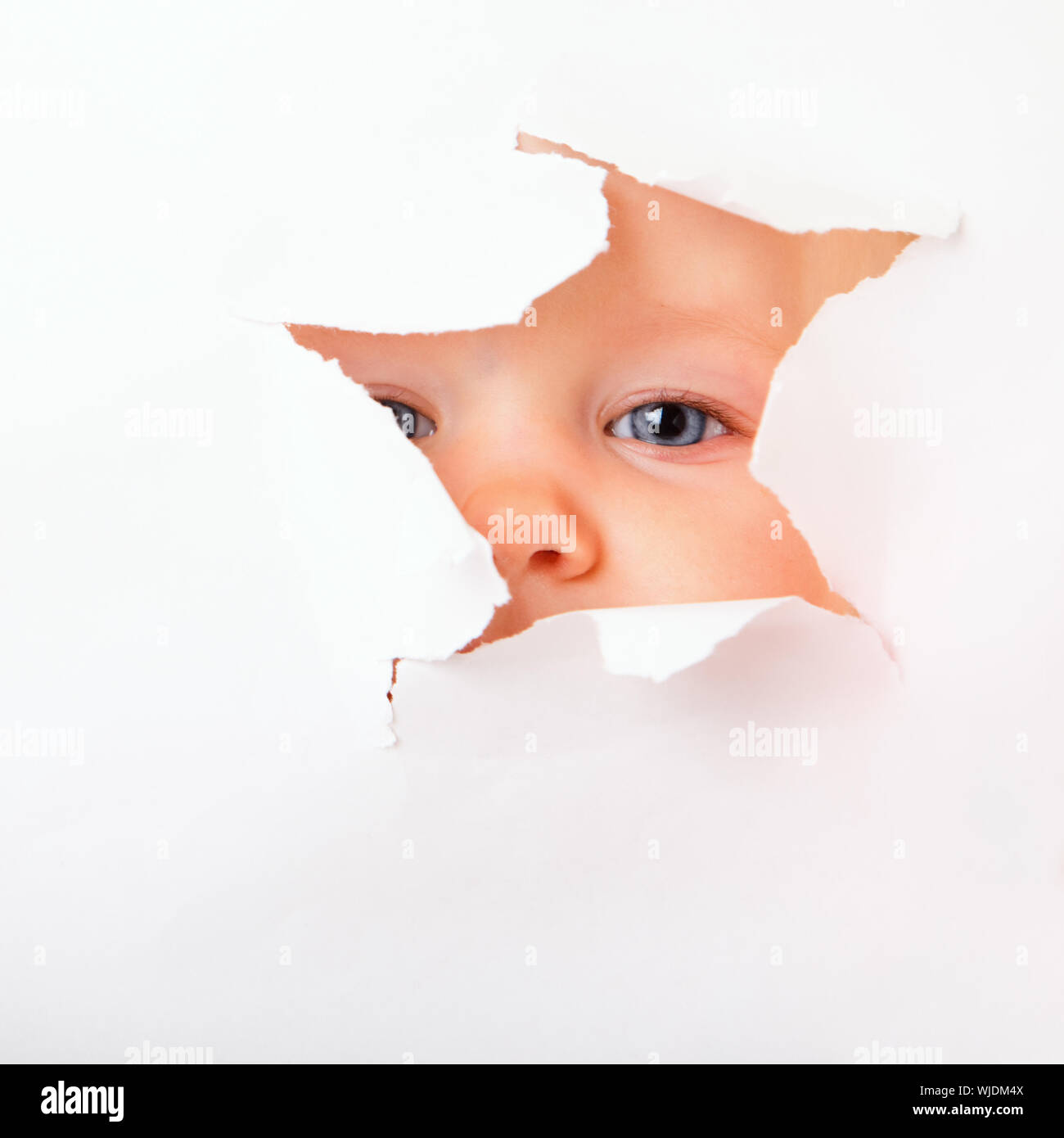 Cute baby girl looking through paper hole Stock Photo - Alamy