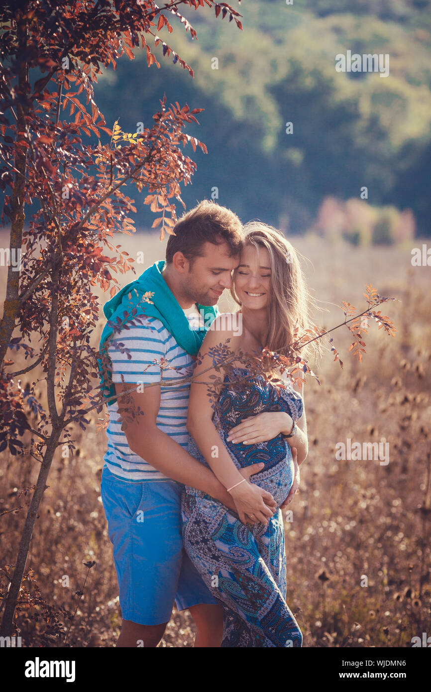 Happy young couple expecting baby, pregnant woman with husband touching ...