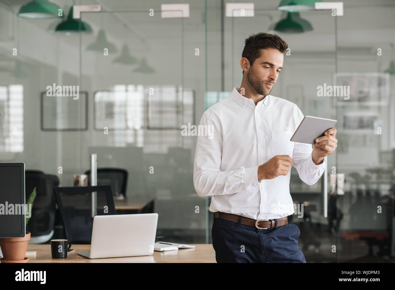 Young businessman standing in an office using a digital tablet Stock ...
