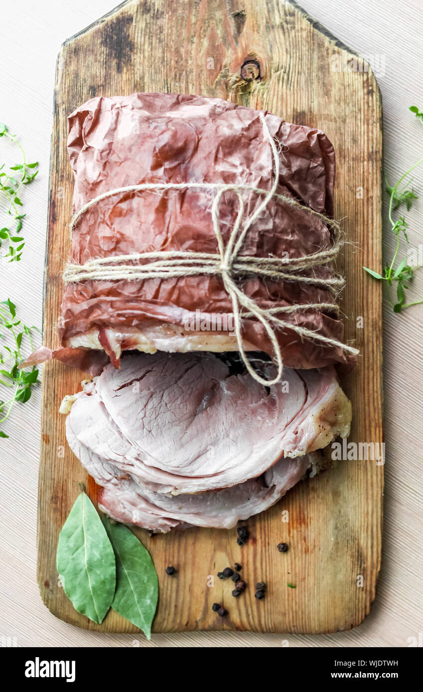 Homemade baked pork ham on rustic cutting board with aromatic herbs ...