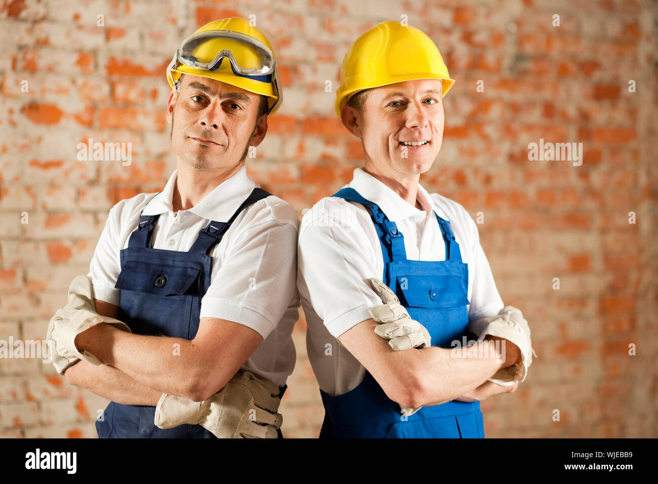 Construction workers standing with folded arms Stock Photo - Alamy