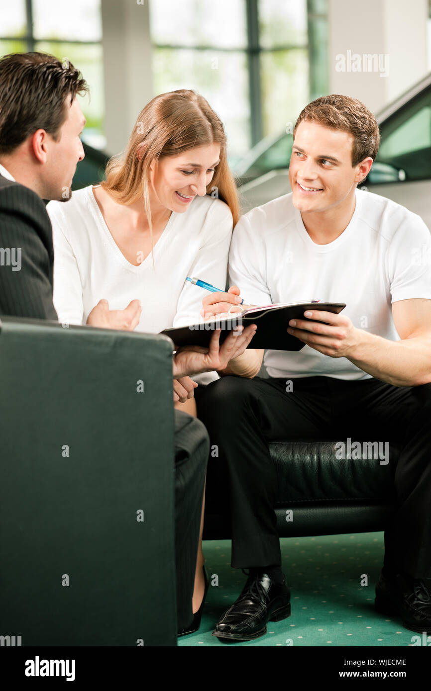 Couple signing sales contract at car dealer Stock Photo - Alamy