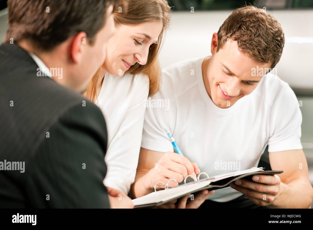 Couple signing sales contract at car dealer Stock Photo - Alamy