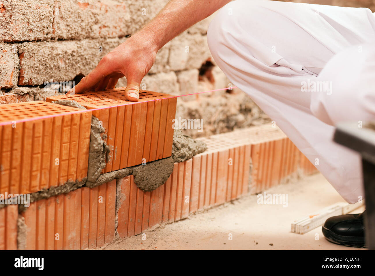 bricklayer with brick on construction site Stock Photo - Alamy