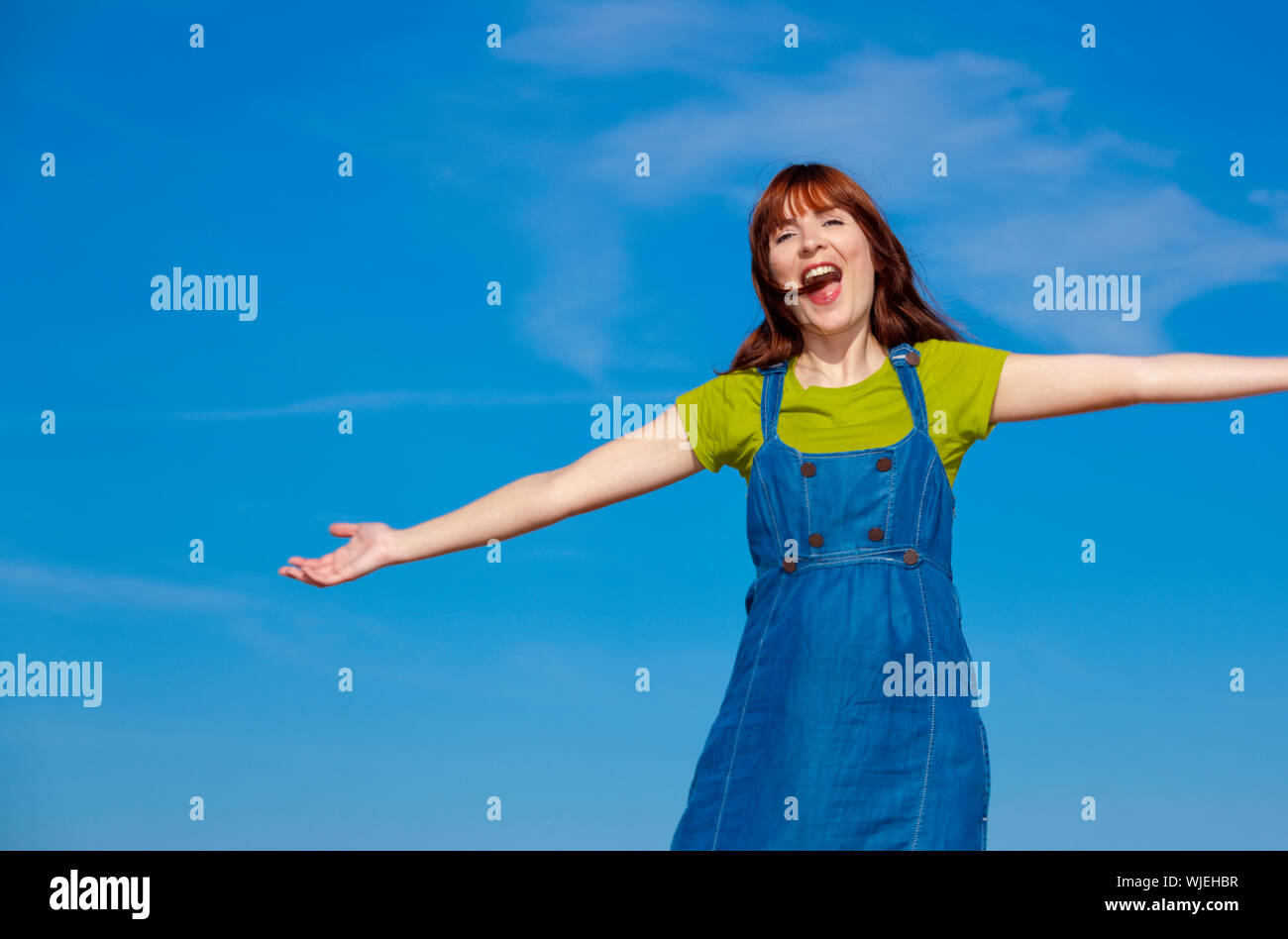 Portrait of a beautiful woman over a blue sky with arms open Stock ...