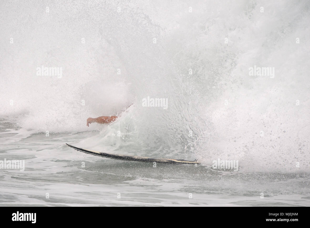Surfer knocked by huge wave from surfboard Stock Photo - Alamy