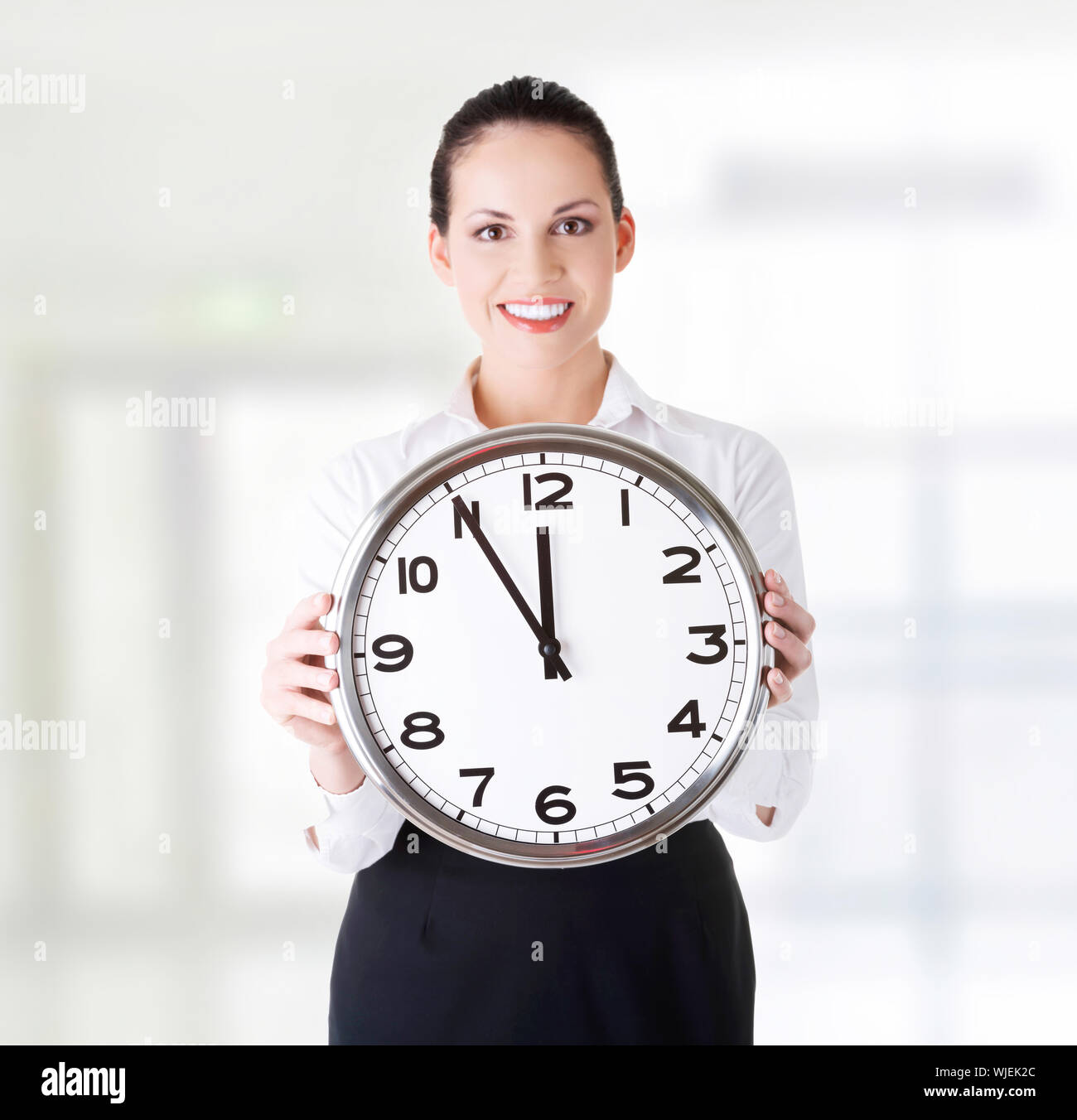 Happy young business woman holding office clock, isolated on white ...
