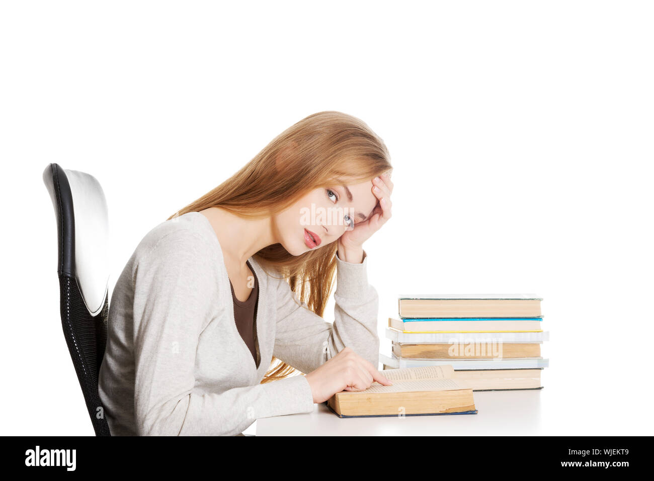 Bored and tired casual student woman sitting by the desk and learning ...