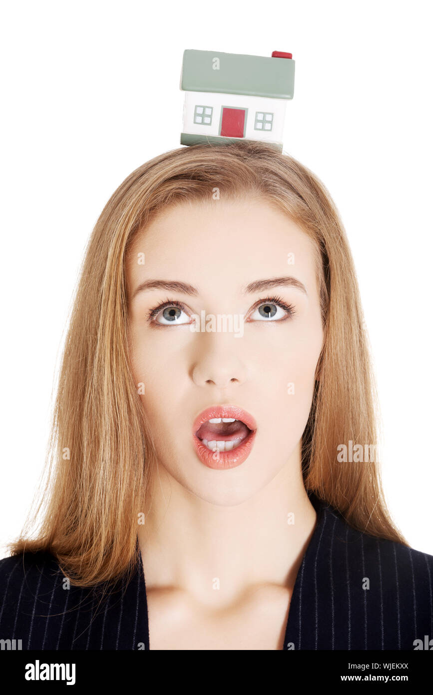 Portrait of beautiful business shocked woman with house on head ...