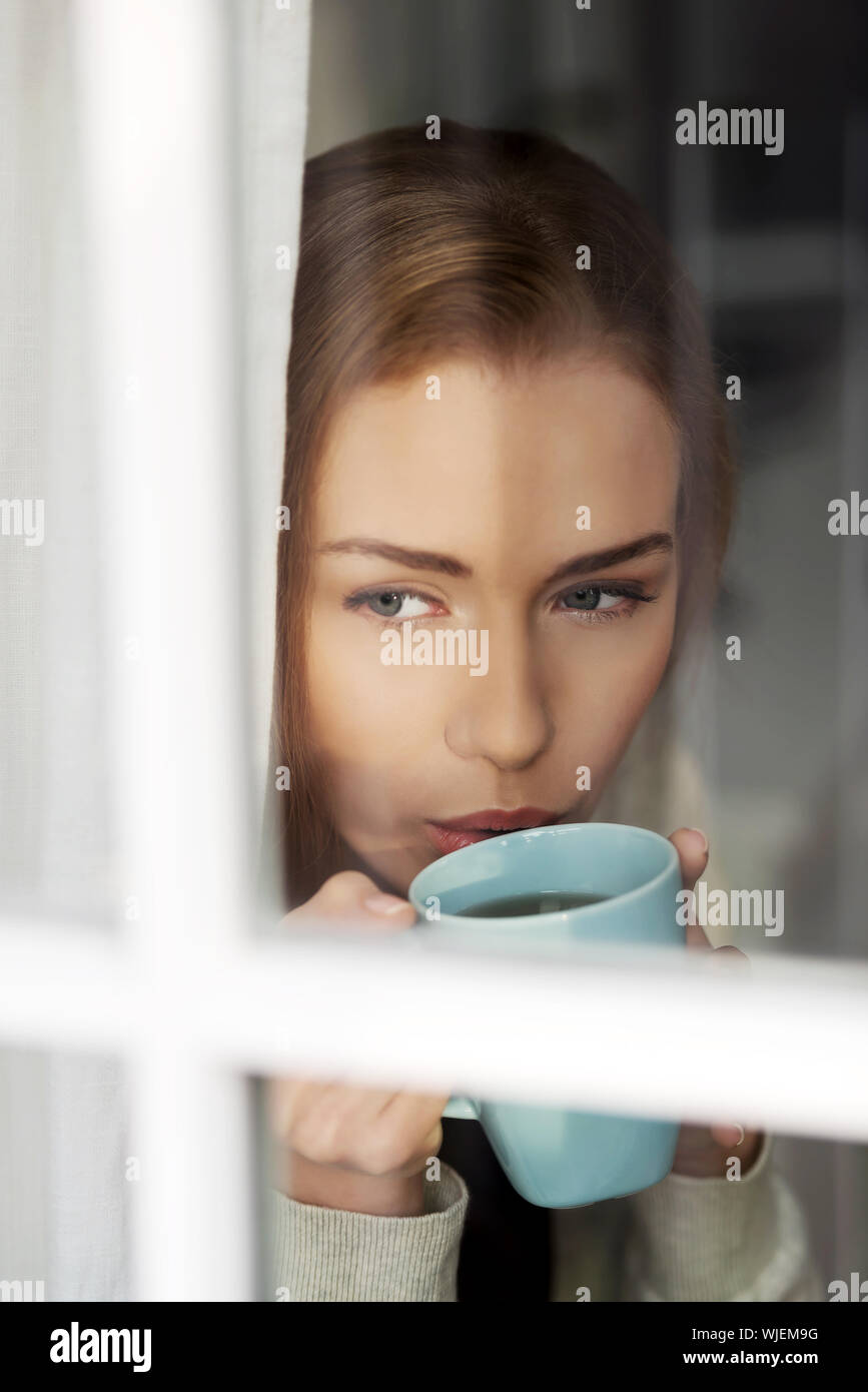 Beautiful caucasian woman drinking hot coffee or tea and looking ...